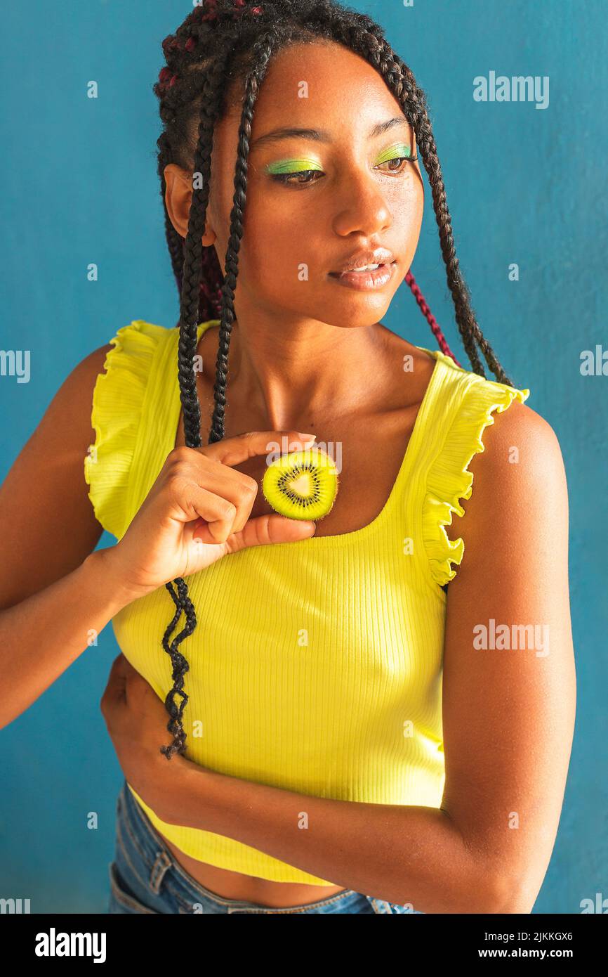 A vertical of a beautiful young mixed race female posing with a kiwi in ...