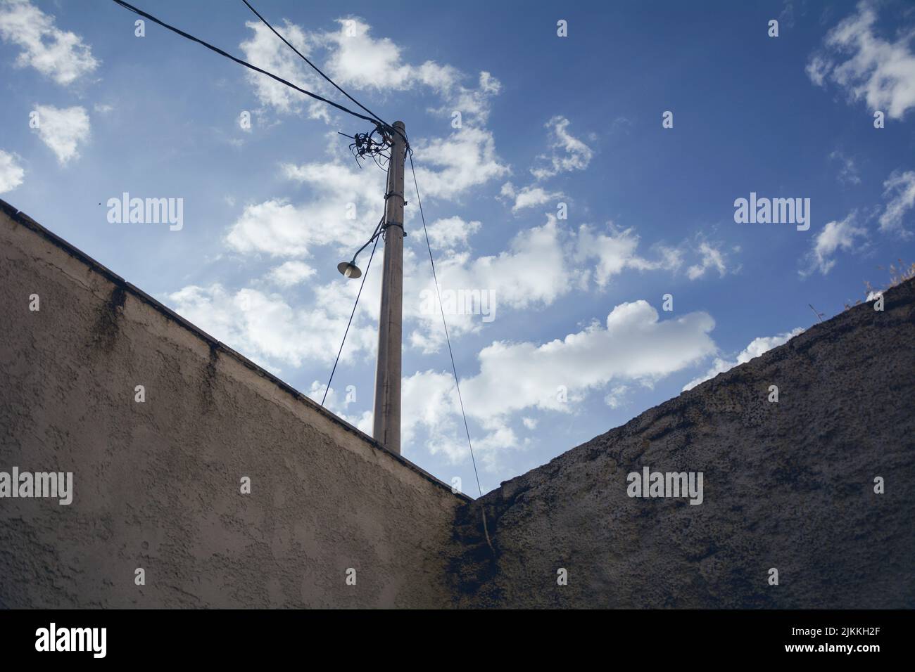 A low-angle shot of two adjacent walls and electric cables above them ...