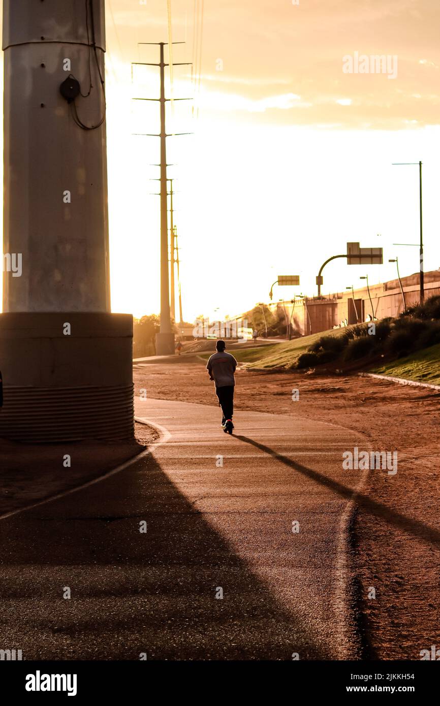 A vertical shot of a man running on a path in the sunset Stock Photo ...