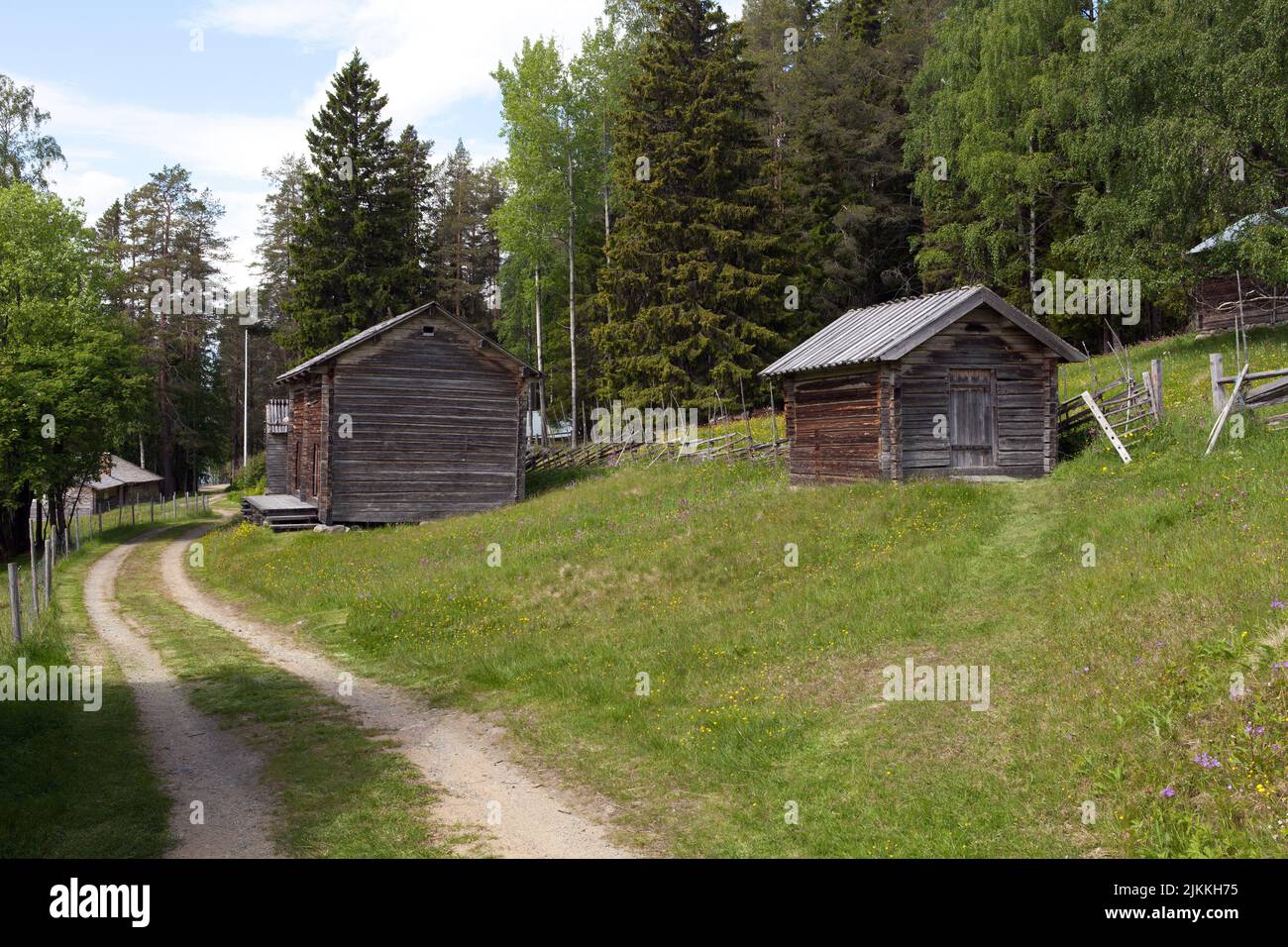 Wooden timber buildings. Gravel road crosses a small village on the ...