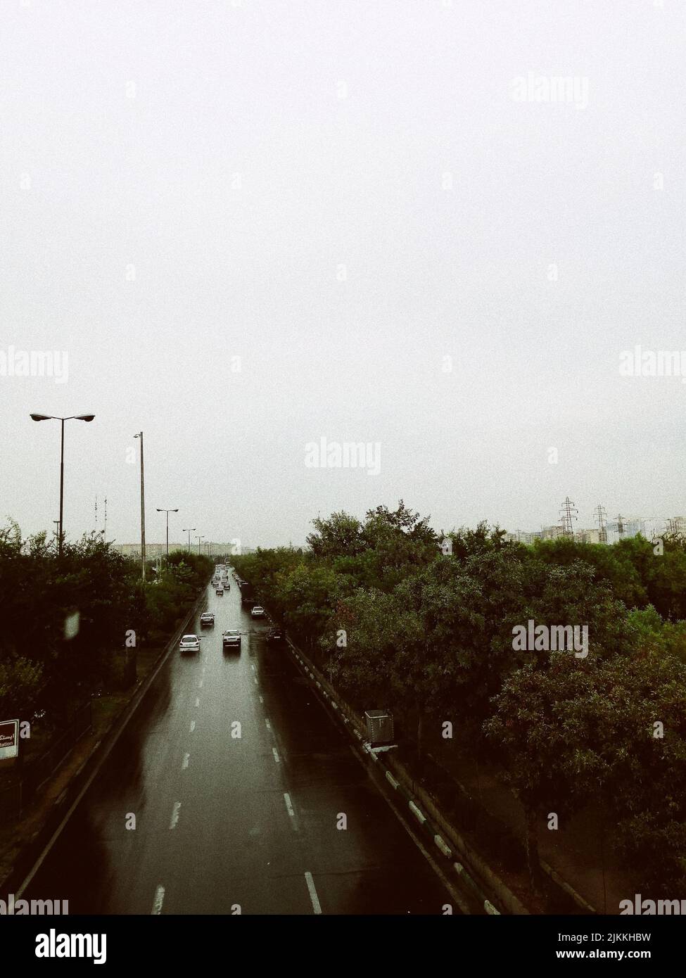 A vertical top view of the cars passing over the road on a rainy day ...