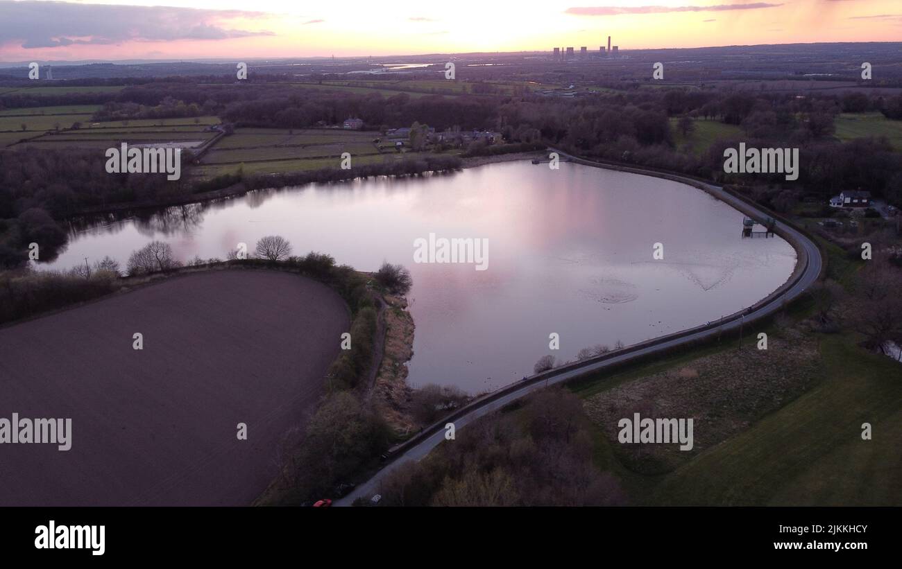 An aerial view of a pond reflecting the sky surrounded by dry plants ...
