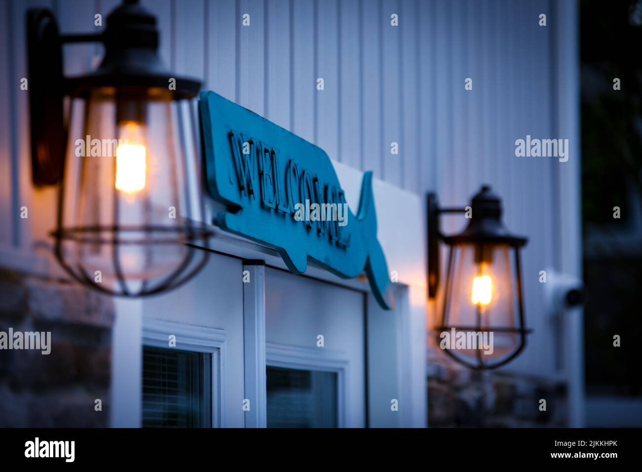 A wooden blue WELCOME sign carved in the shape of a fish is suspended ...