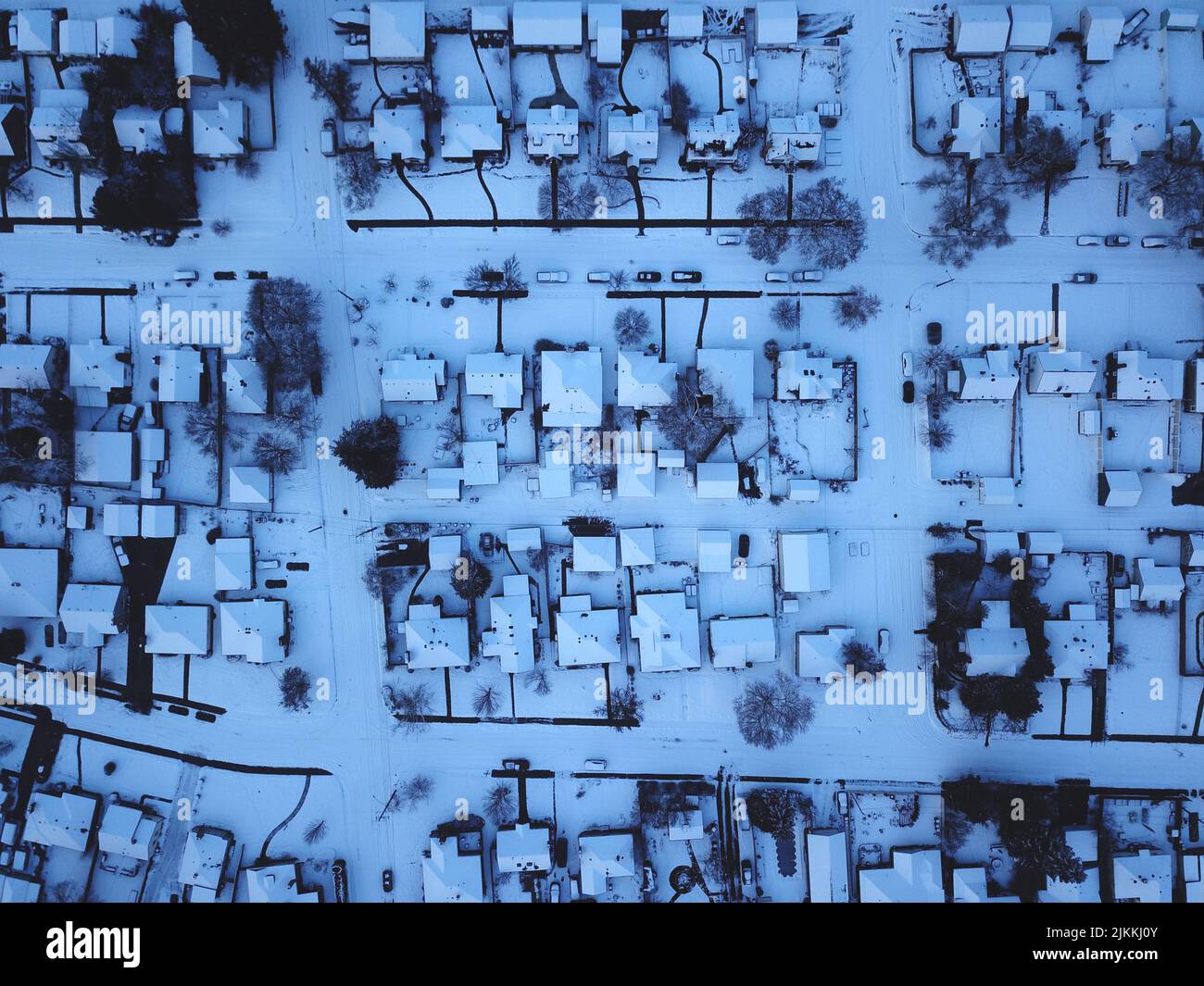 A top view of a beautiful snowy neighborhood with greenery covered in ...
