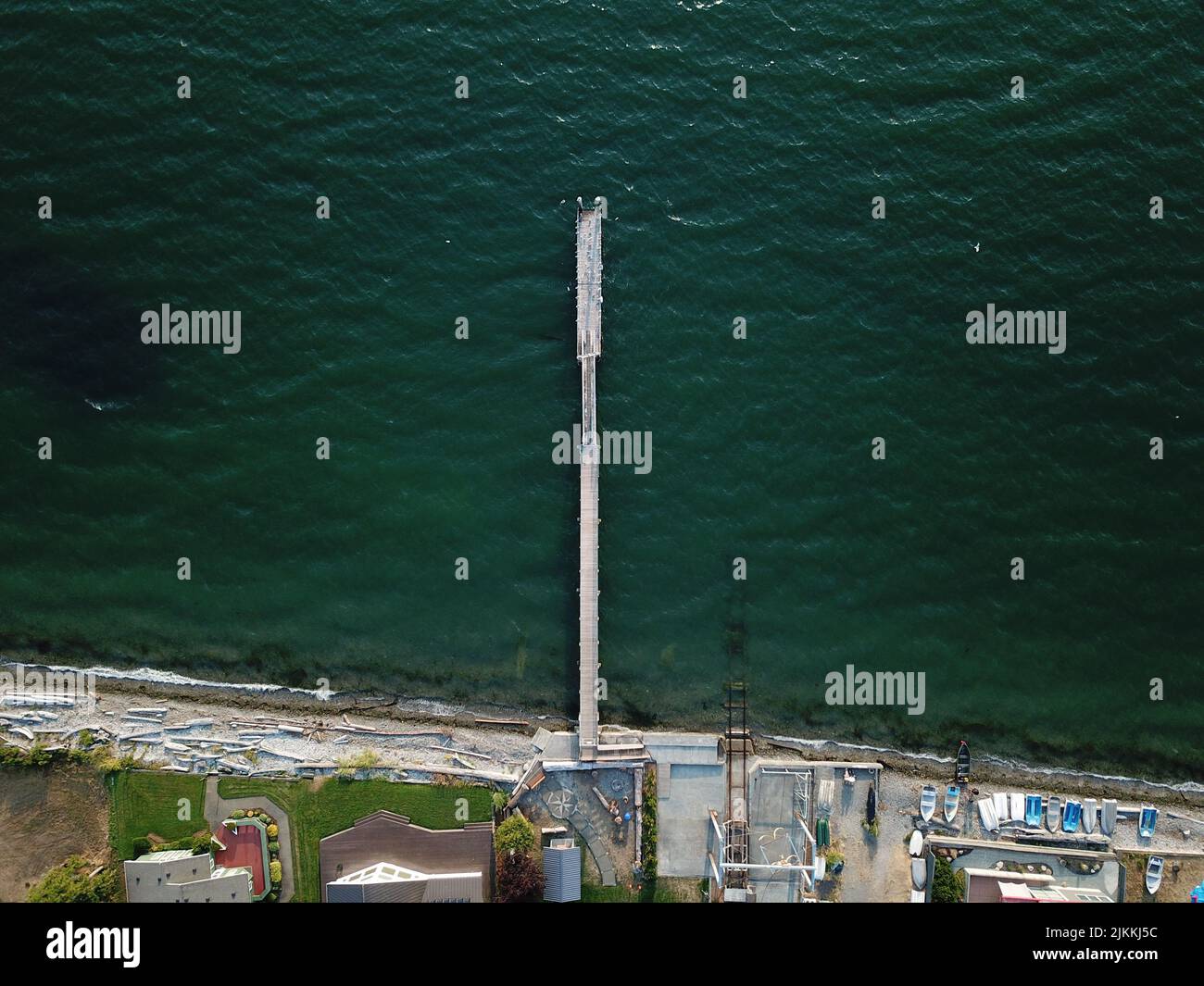 A bird's eye view of the beautiful dark green ocean with a thin wooden ...