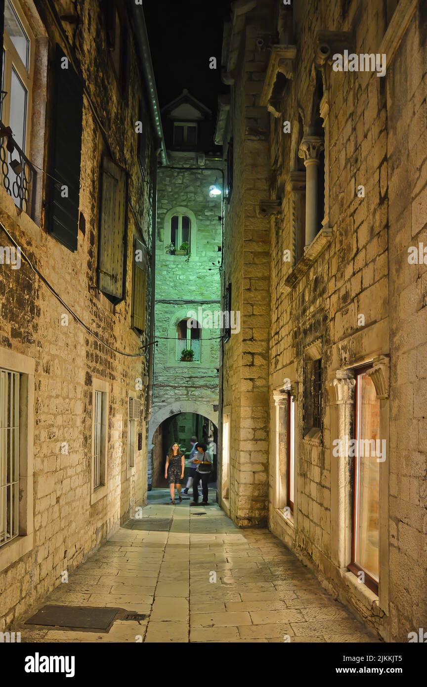 A vertical shot of people walking in a narrow street in the medieval ...