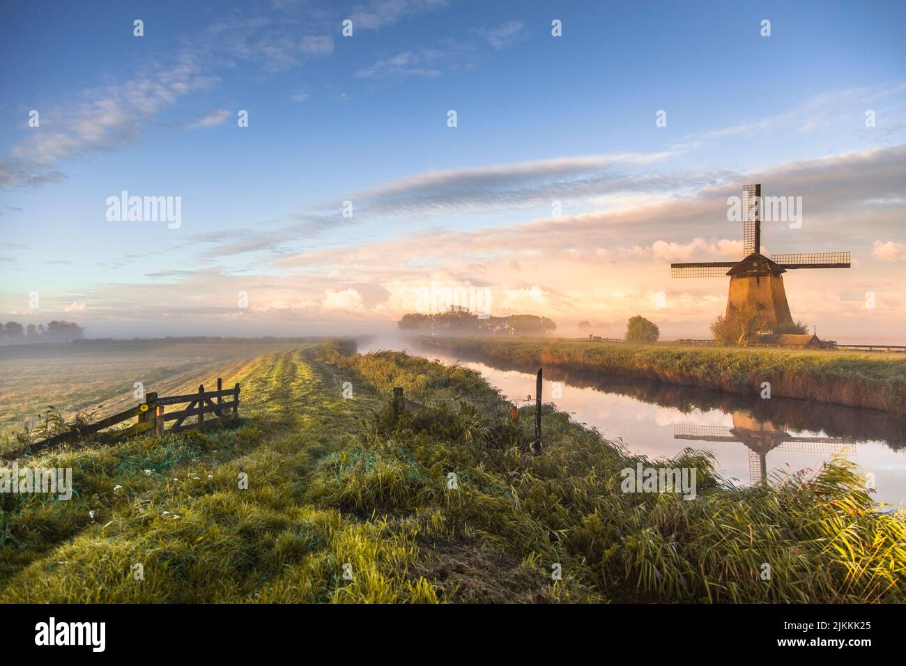 A windmill and sunset sky reflected in a river Stock Photo - Alamy