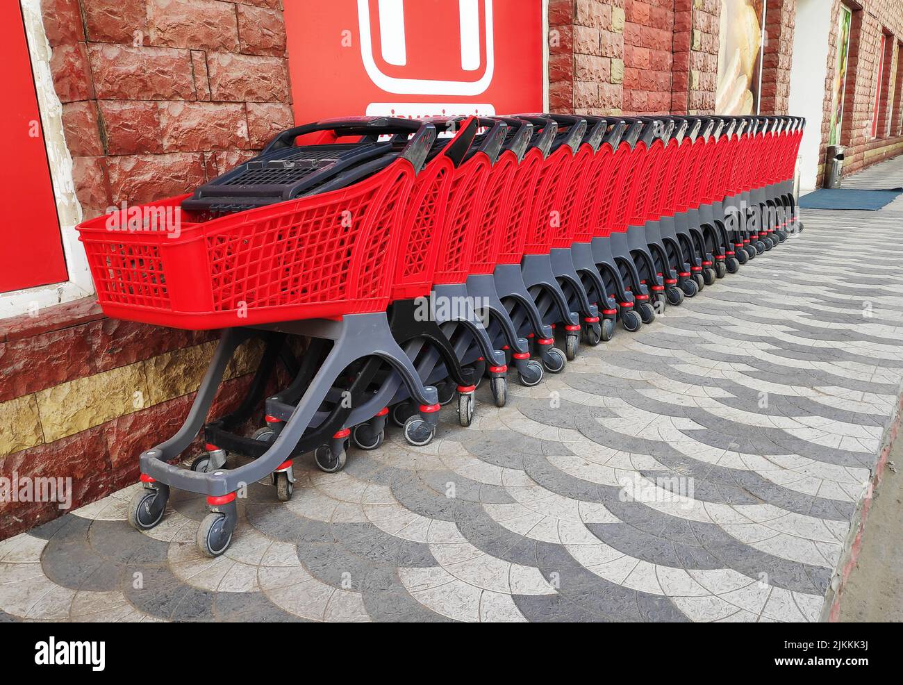 Row of red plastic shopping carts parking in the supermarket. Concept ...