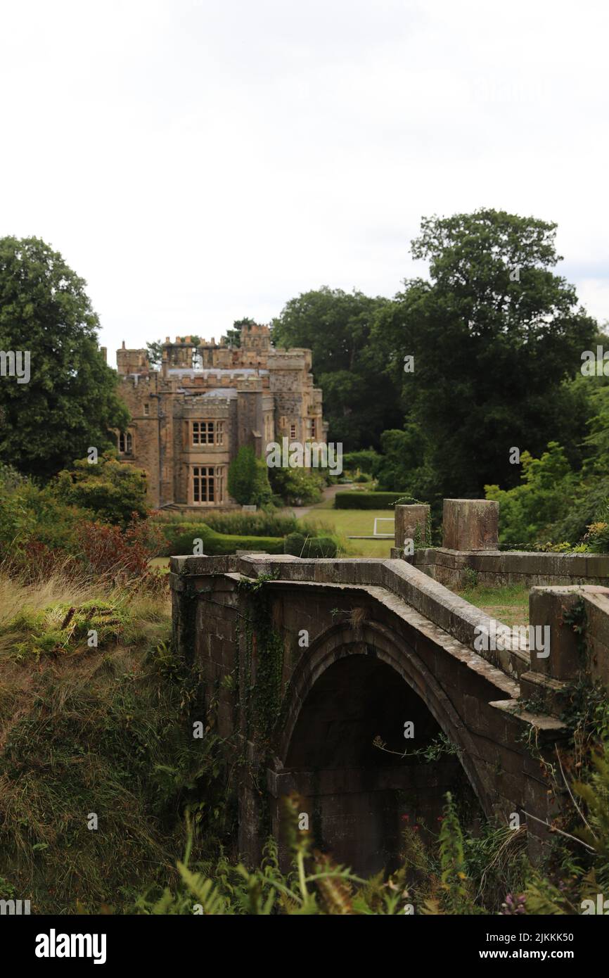 A vertical shot of the stone Hawarden Castle by a bridge in Hawarden ...