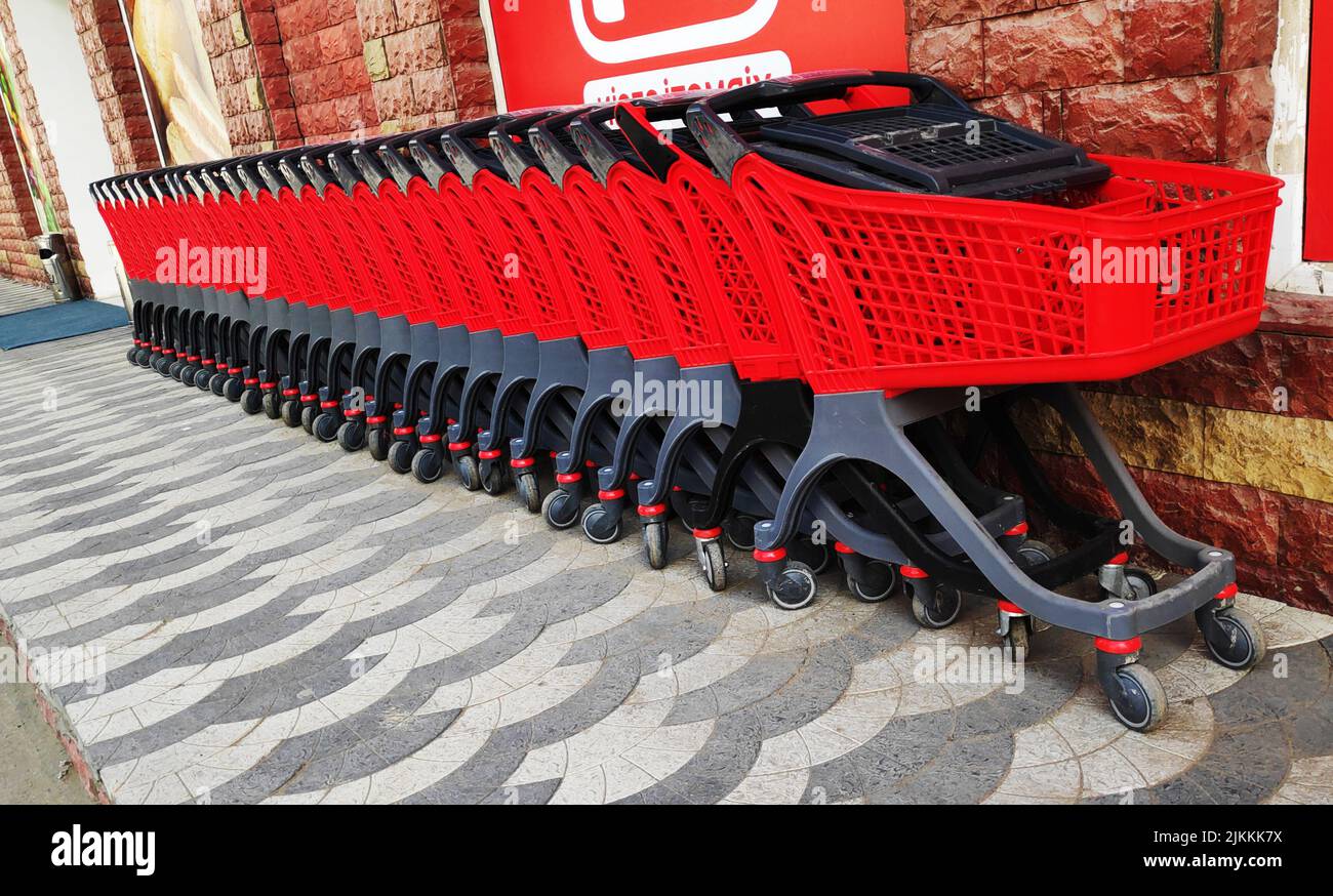 Row of red plastic shopping carts parking in the supermarket. Concept ...