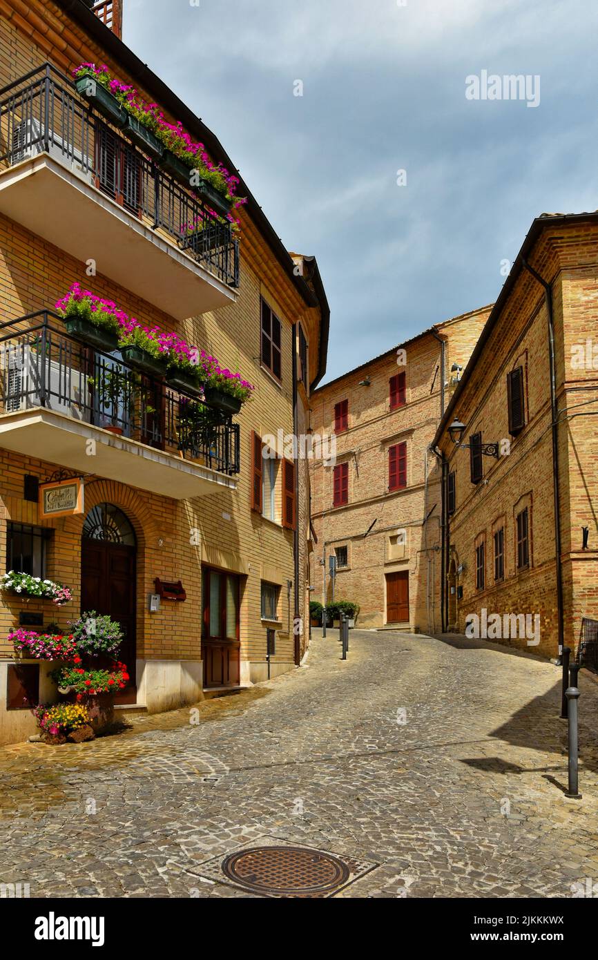 A narrow street between the old houses of Montecosaro, a medieval town ...