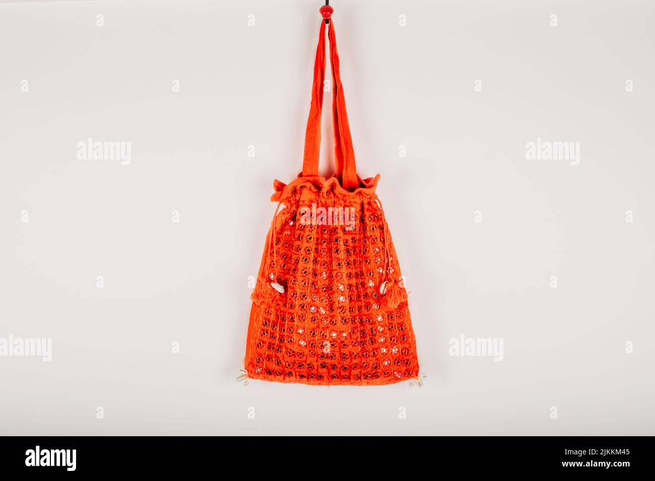 A dark orange eco-friendly bag hung from above isolated on white ...