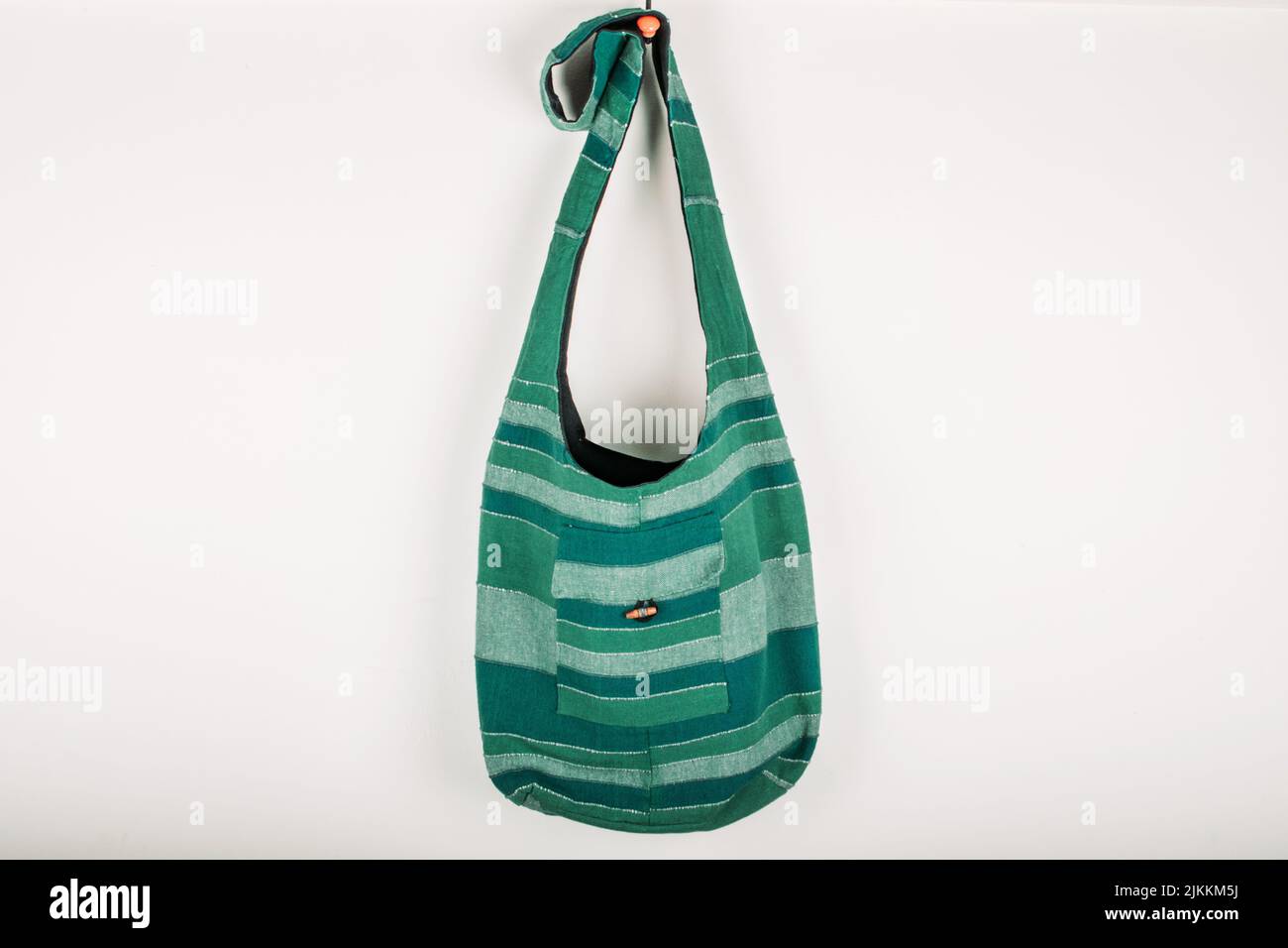 A green eco-friendly bag hung from above isolated on white background ...