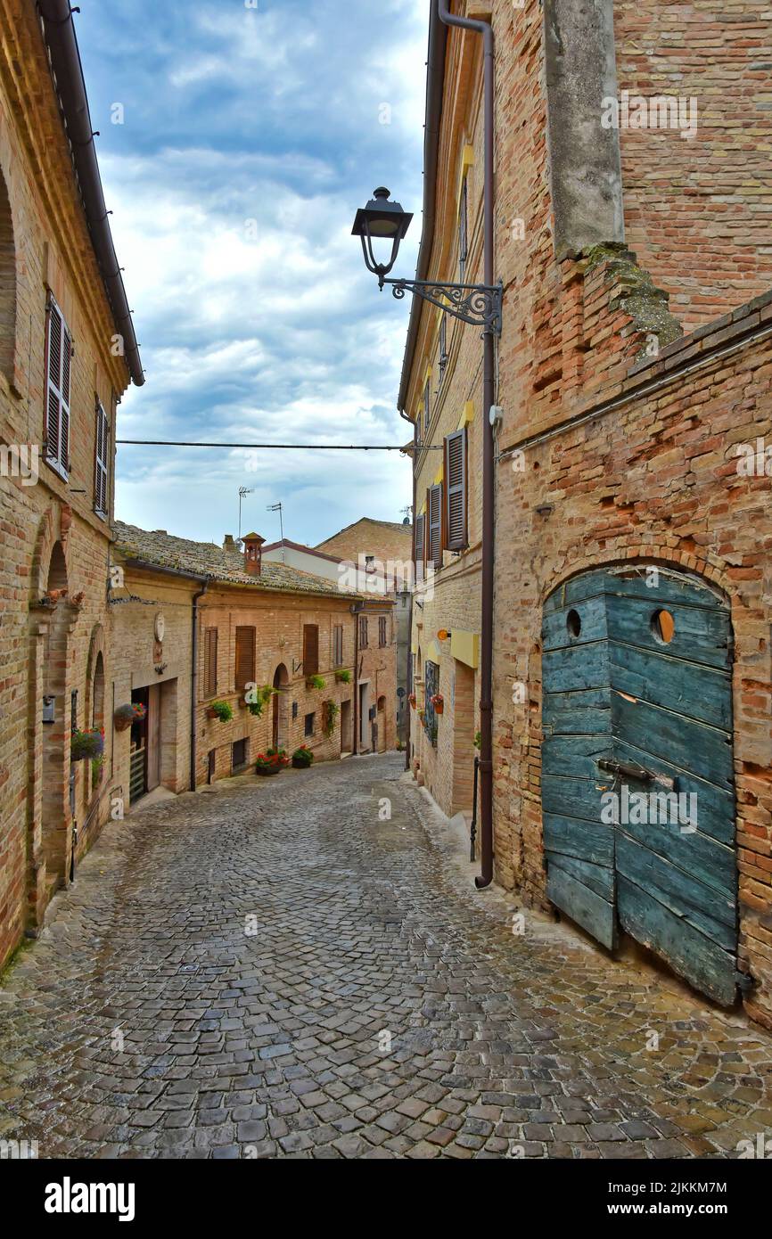 A narrow street between the old houses of Montecosaro, a medieval town ...