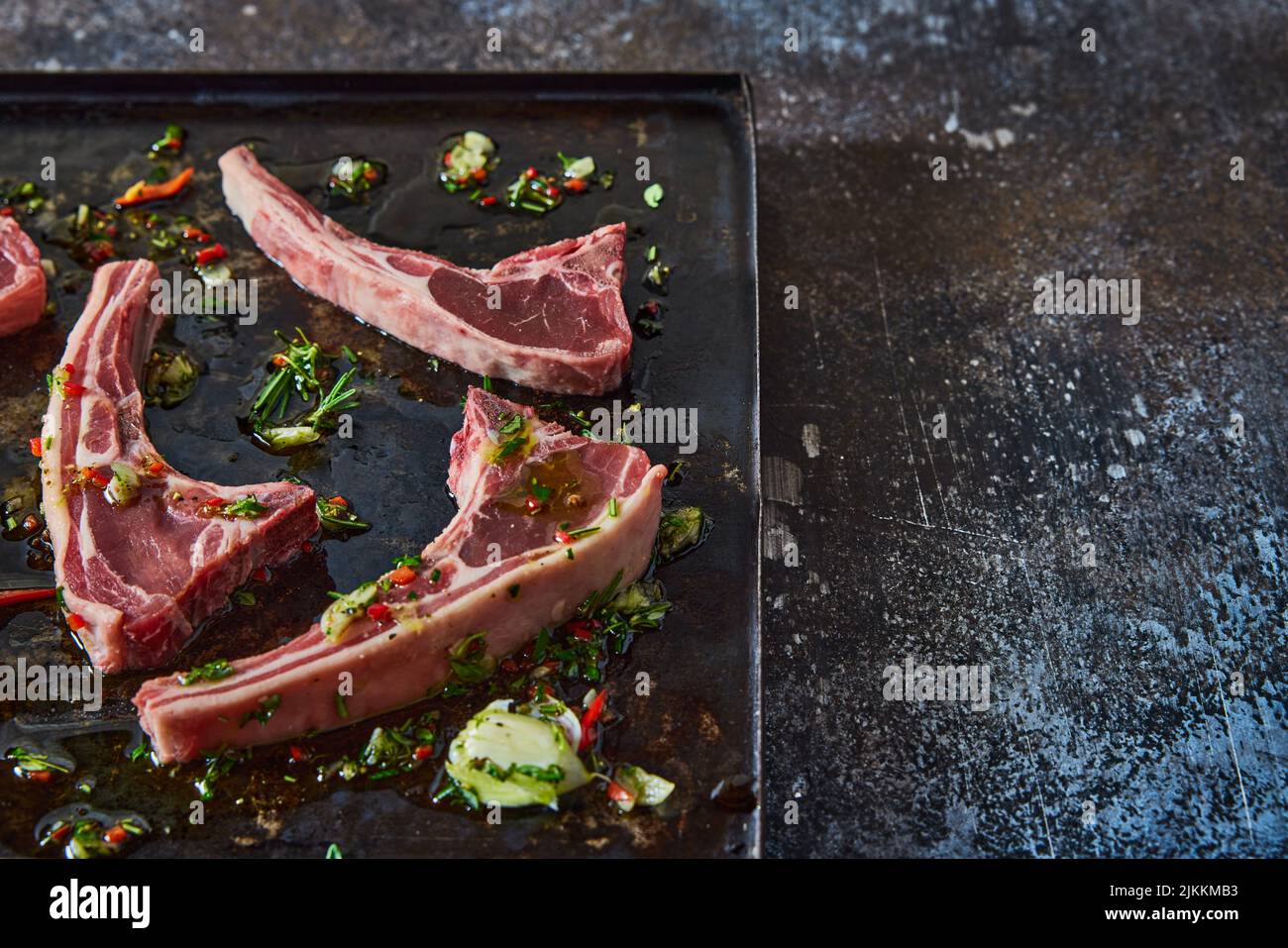 From above of uncooked lamb chops placed on black tray with chopped ...