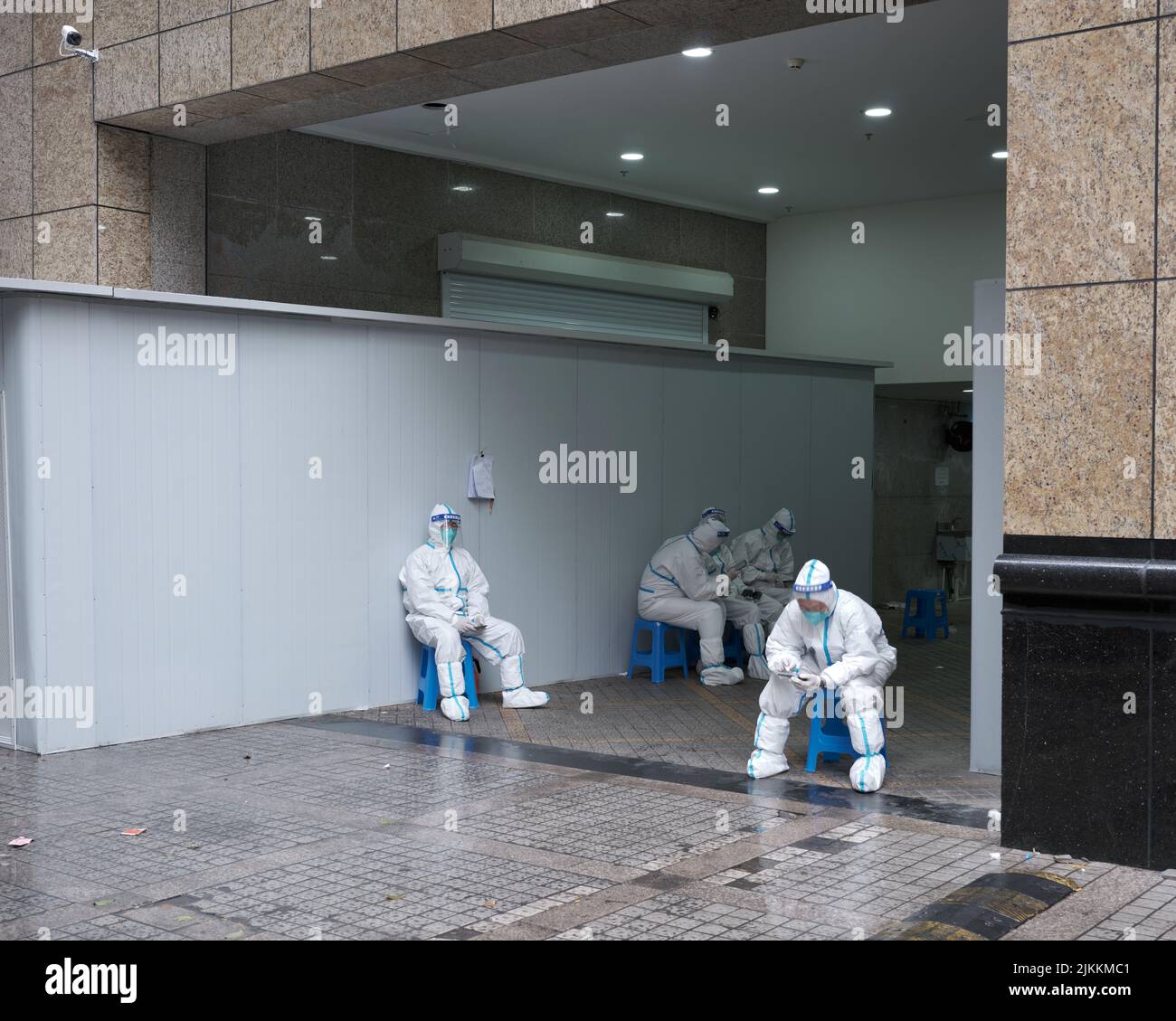 The healthcare workers in hazmat suits taking a rest on the ground ...