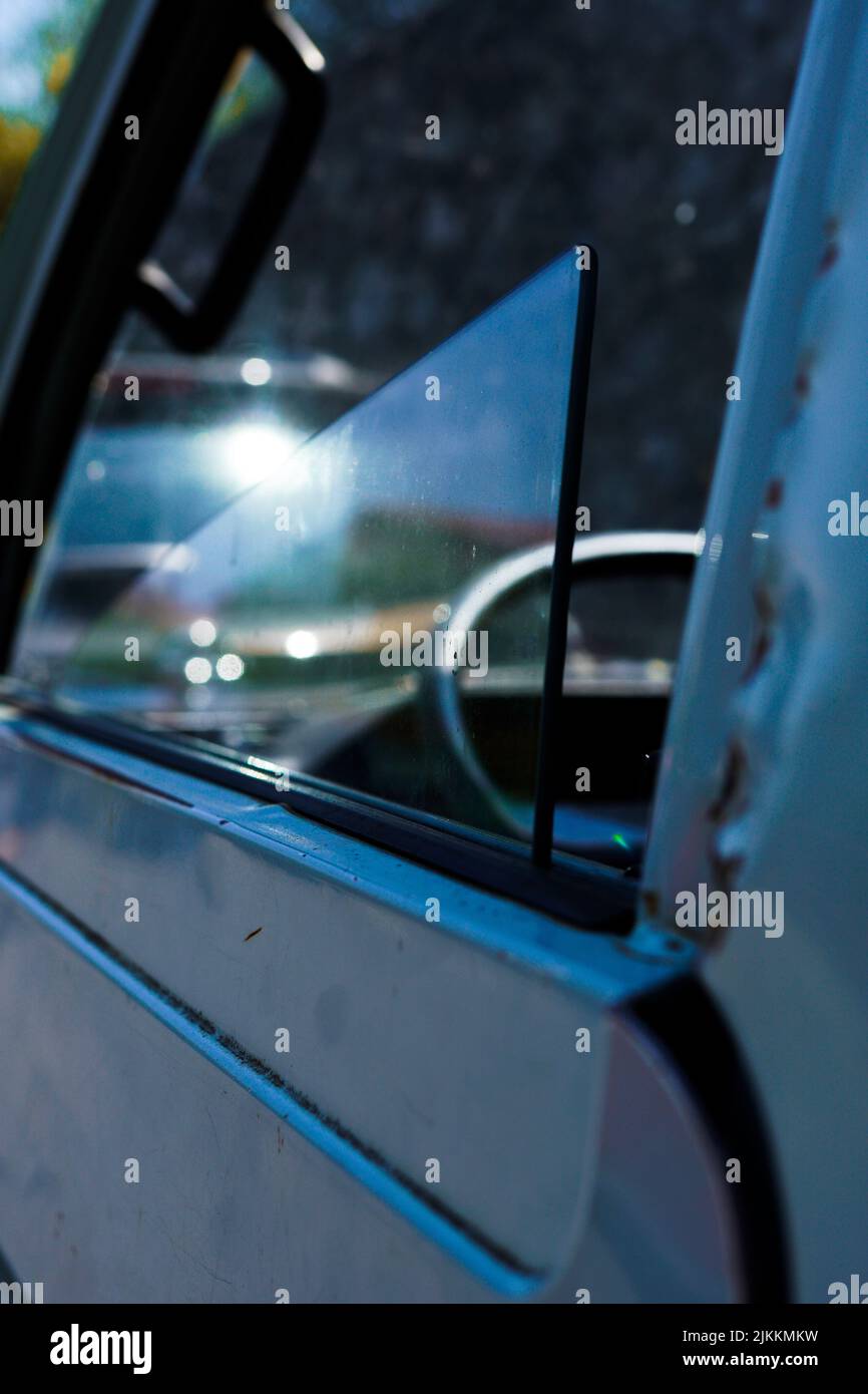 A vertical closeup of the sunlight reflecting on the car window glass ...