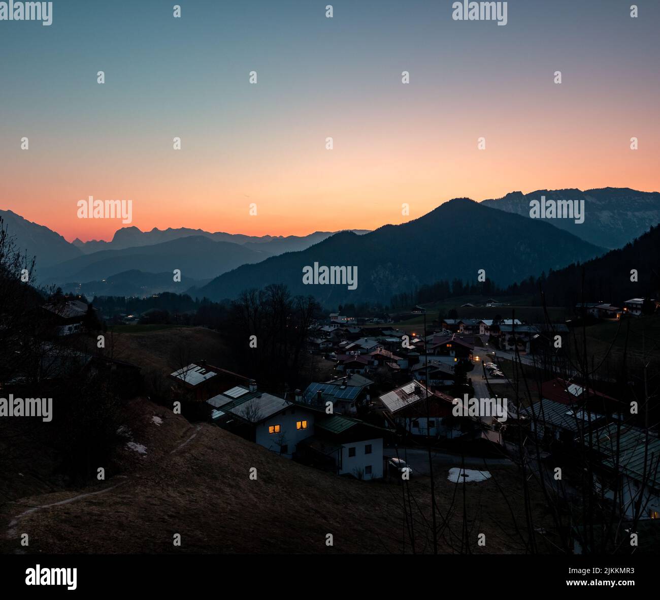 The view of a village with mountains range in the background at sunset ...
