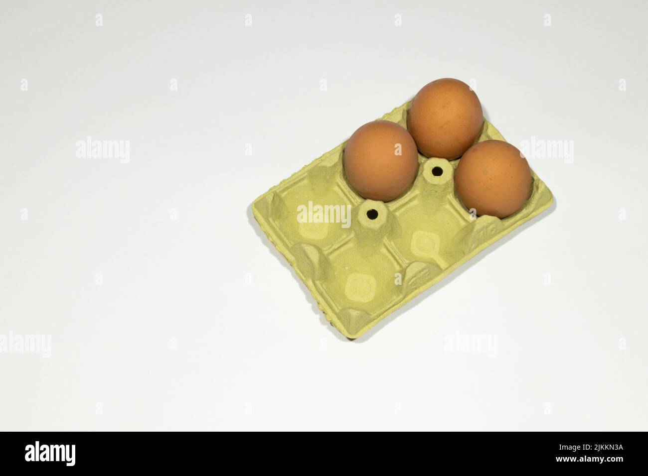 A top view of an egg carton with three eggs and three empty spots Stock ...