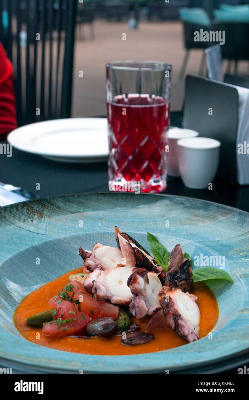 Fried octopus in tomato sauce with olives and capers in a blue plate ...