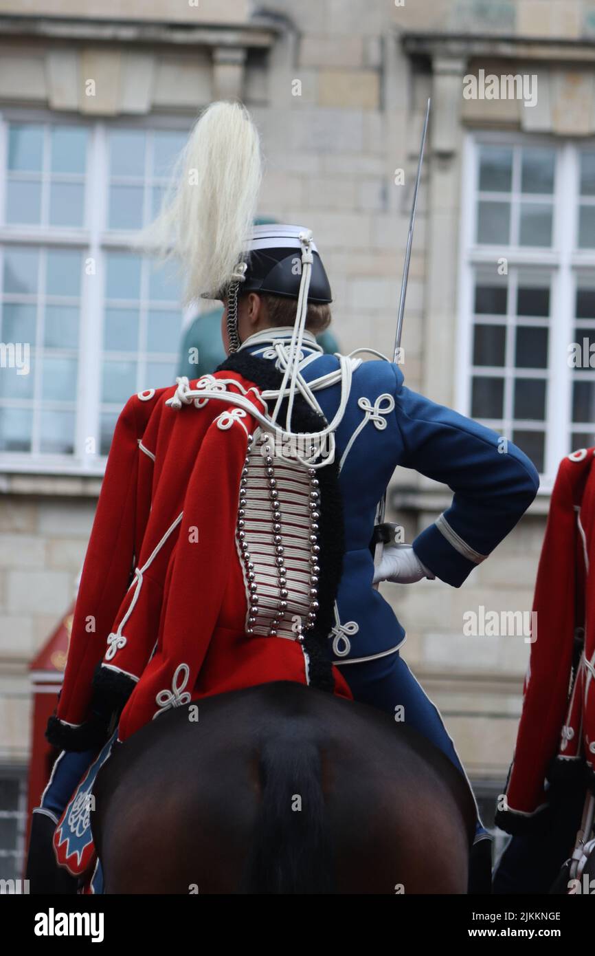 A vertical, back view of a man with military uniform riding a horse ...