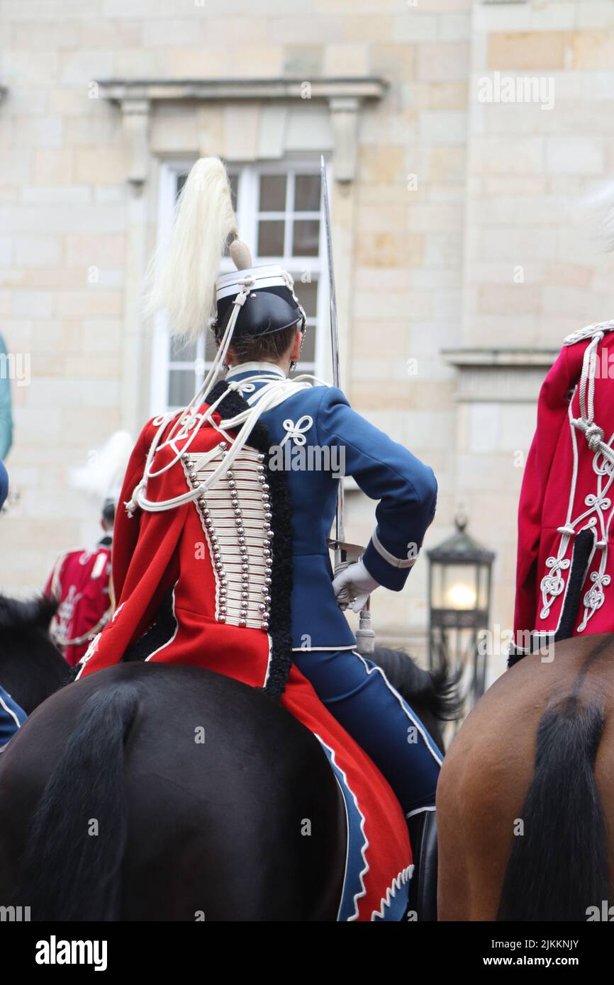 A vertical, back view of a man with military uniform riding a horse ...