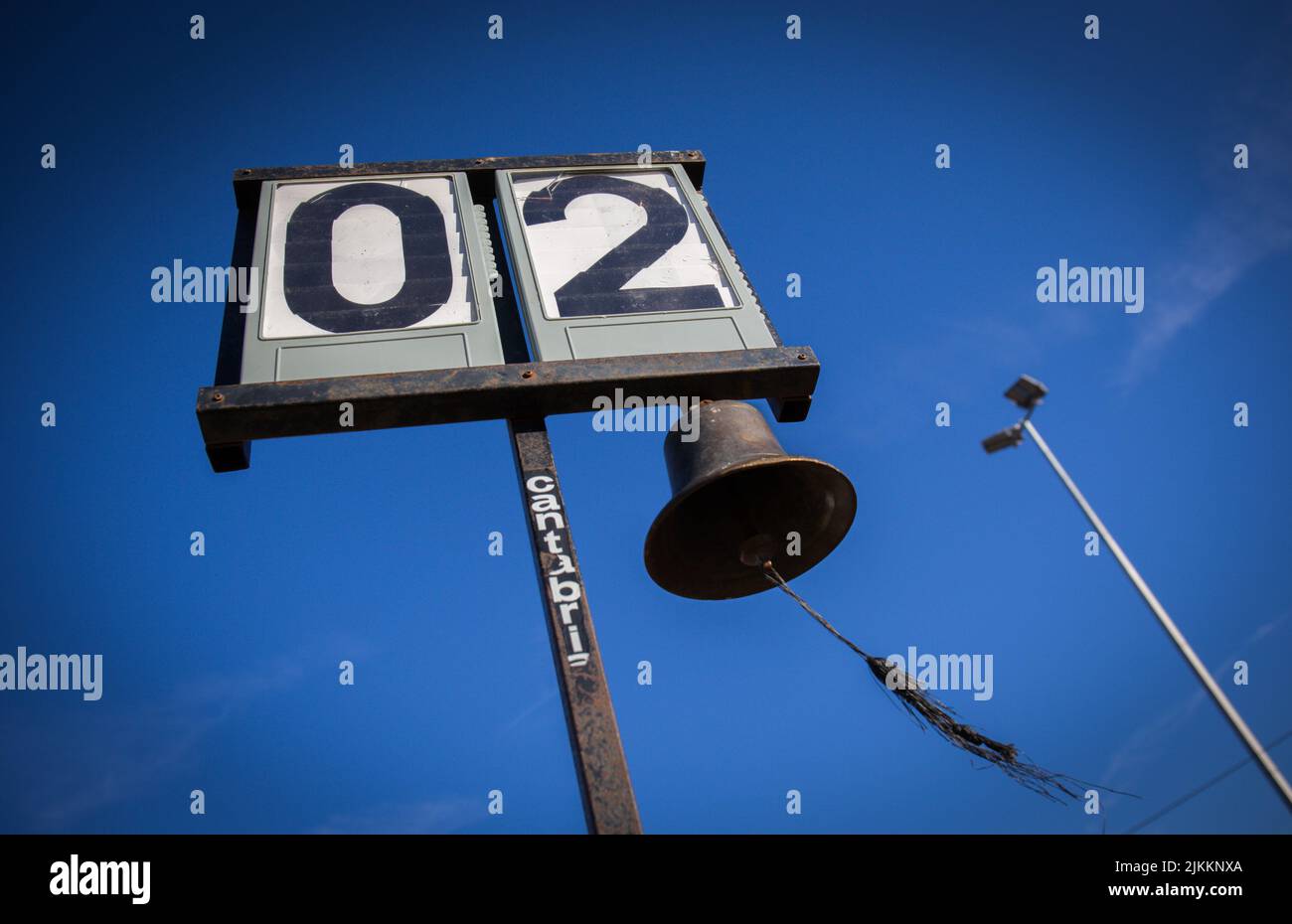 A low angle shot of an old flip clock on a metal pole and a big metal ...