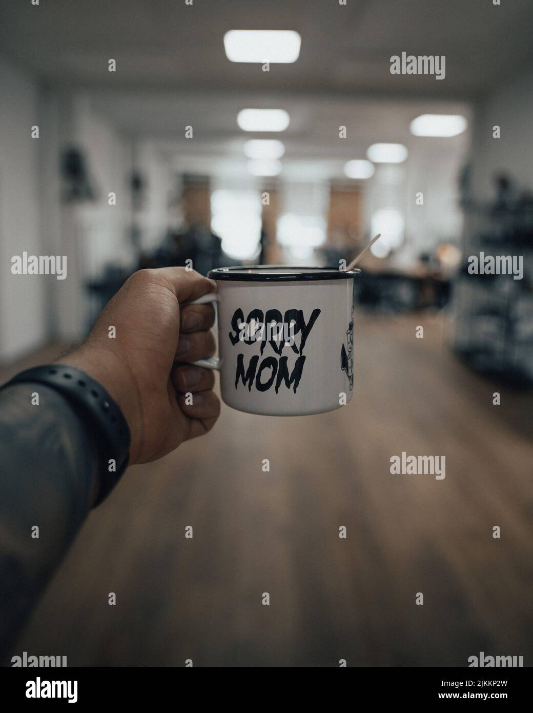 A human hand holding cup with 'sorry mom' text in blurred background ...