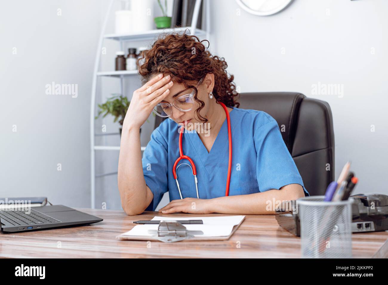 Tired, depressed female doctor sitting alone in the office Stock Photo ...