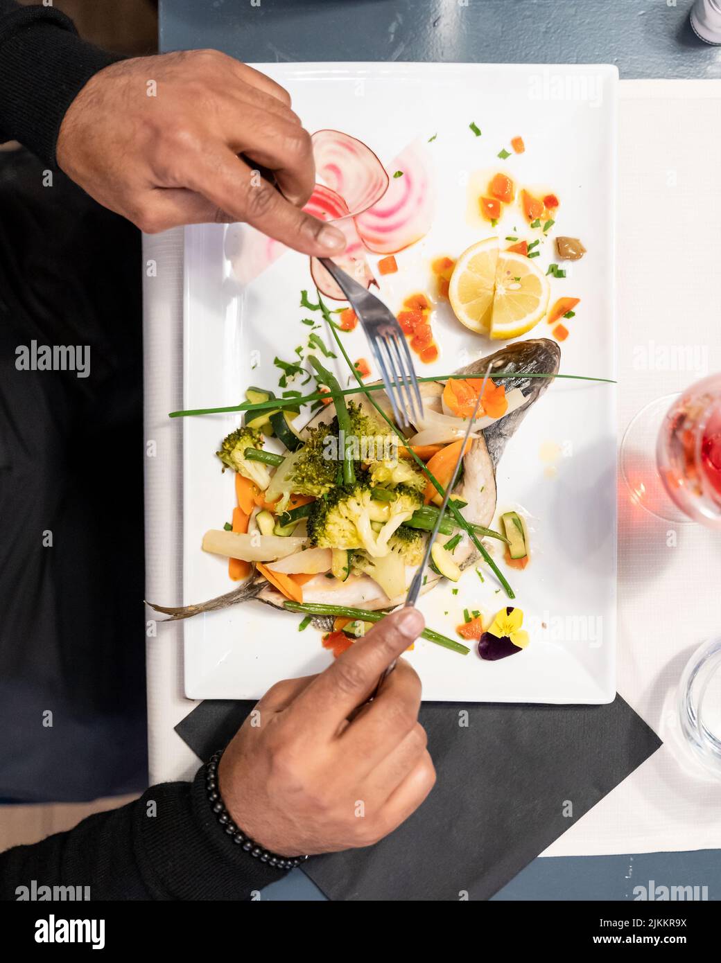 A vertical shot of a person preparing to a eat a gourmet vegetable dish ...