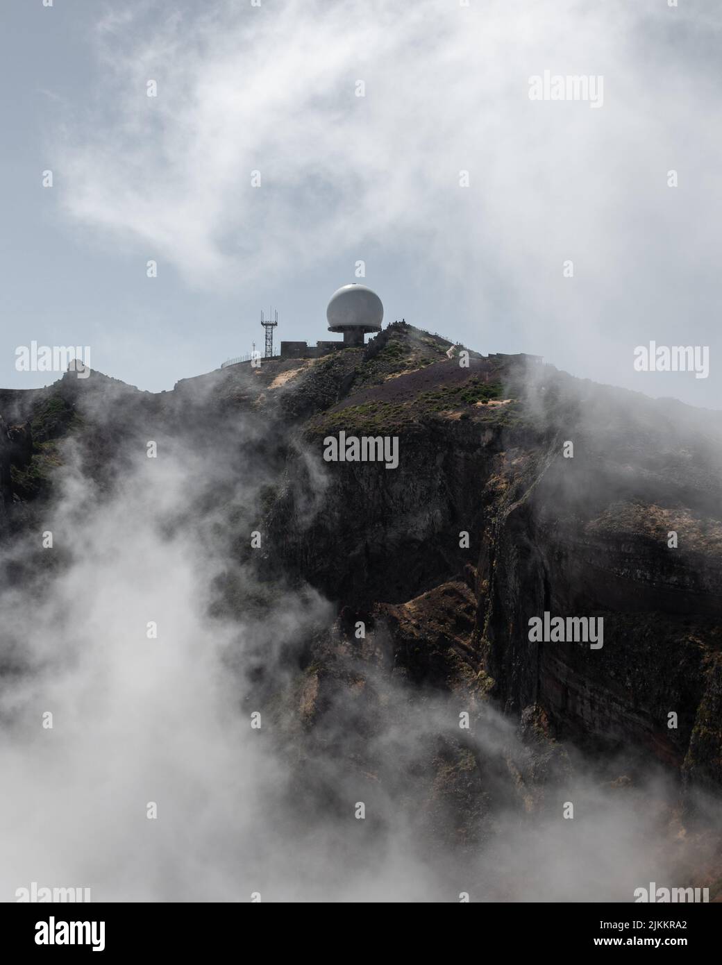 A vertical image of an observatory on top of a mountain covered with a ...