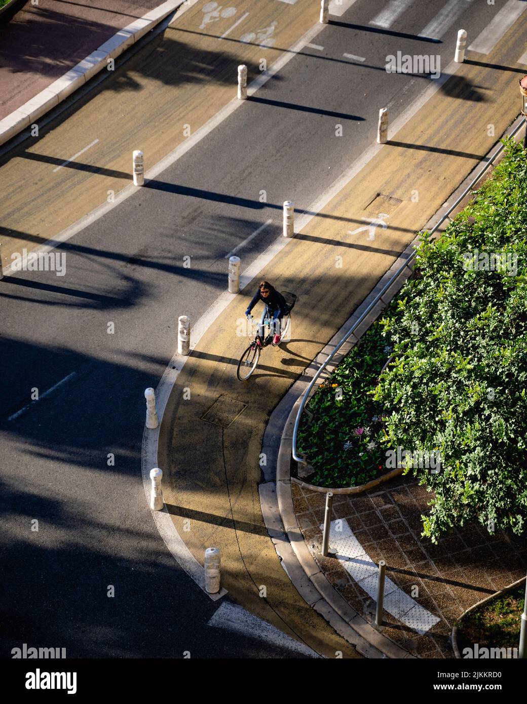 A vertical aerial view of a female riding a bike in the street in Nice ...