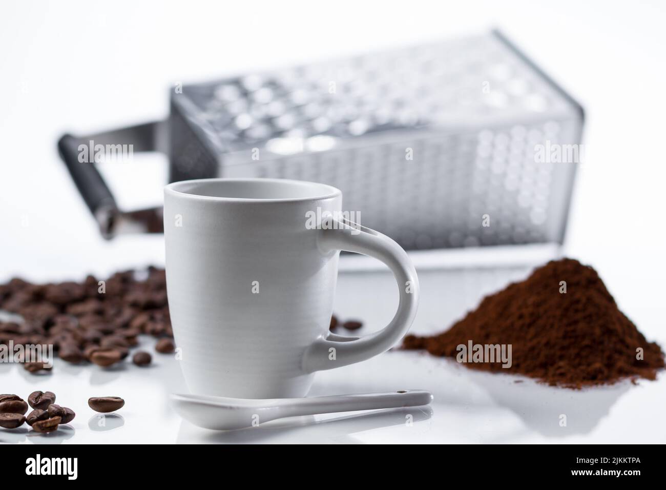 A Shallow focus of a white coffee mug with coffee beans and powder with ...