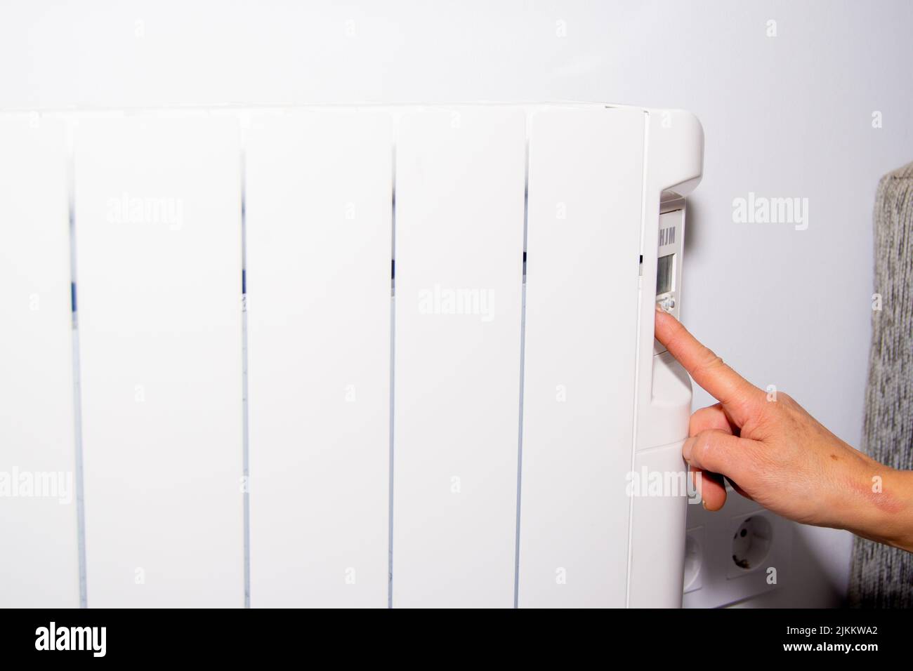 Hand turning on white electric radiator of a house in winter Stock ...
