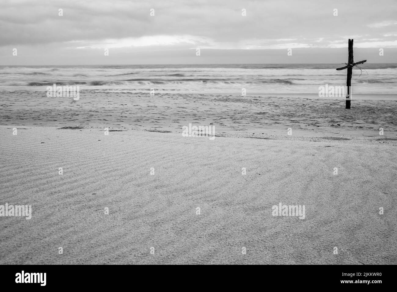 A grayscale shot of a cross on the sandy beach Stock Photo - Alamy