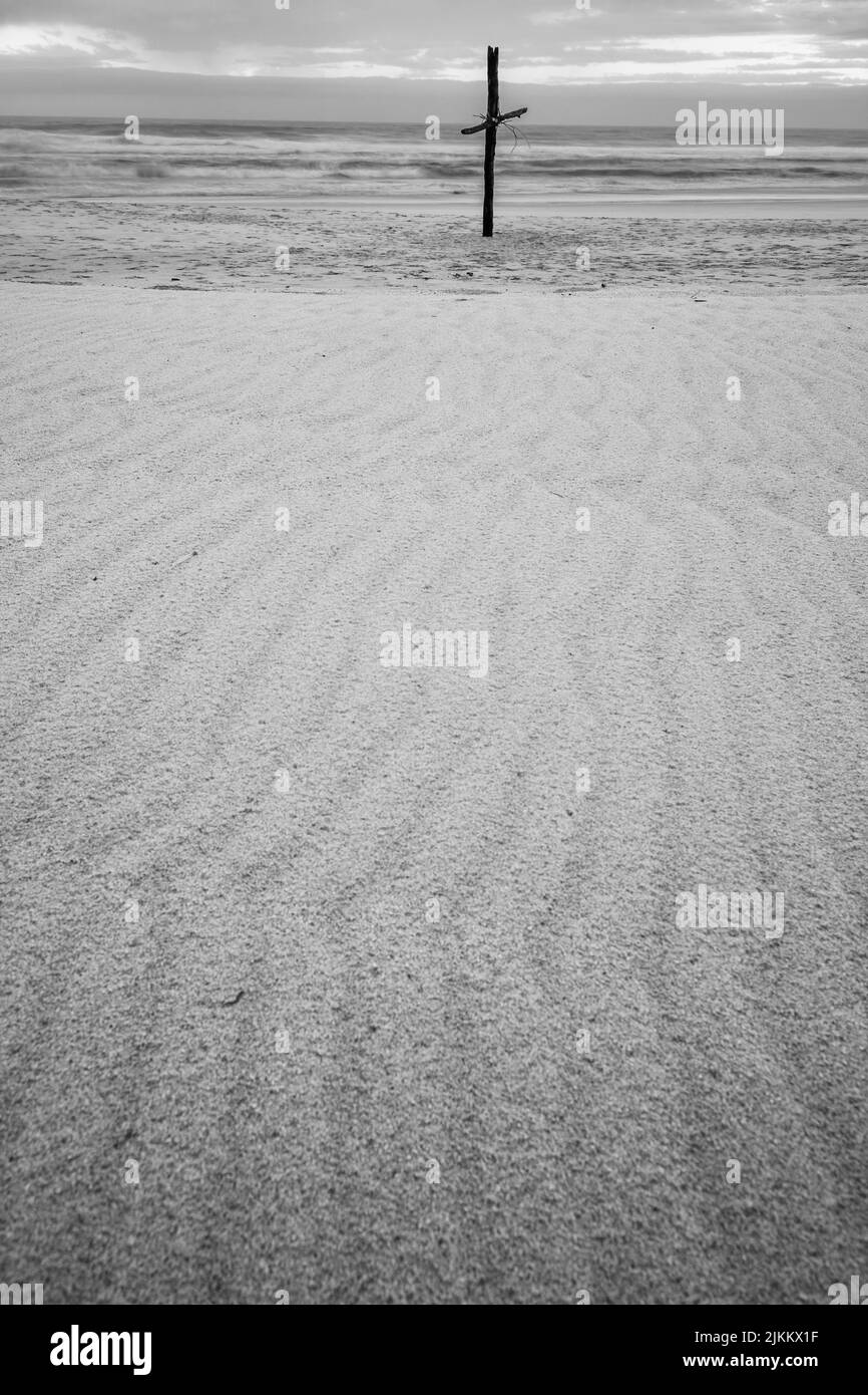 A grayscale shot of a cross on the sandy beach Stock Photo - Alamy