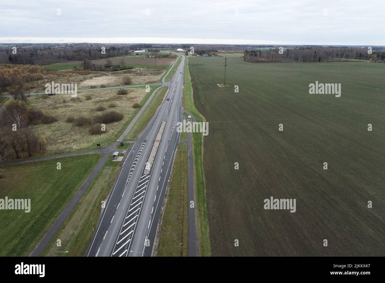 A drone view of highway road with big farms on its sides under cloudy ...