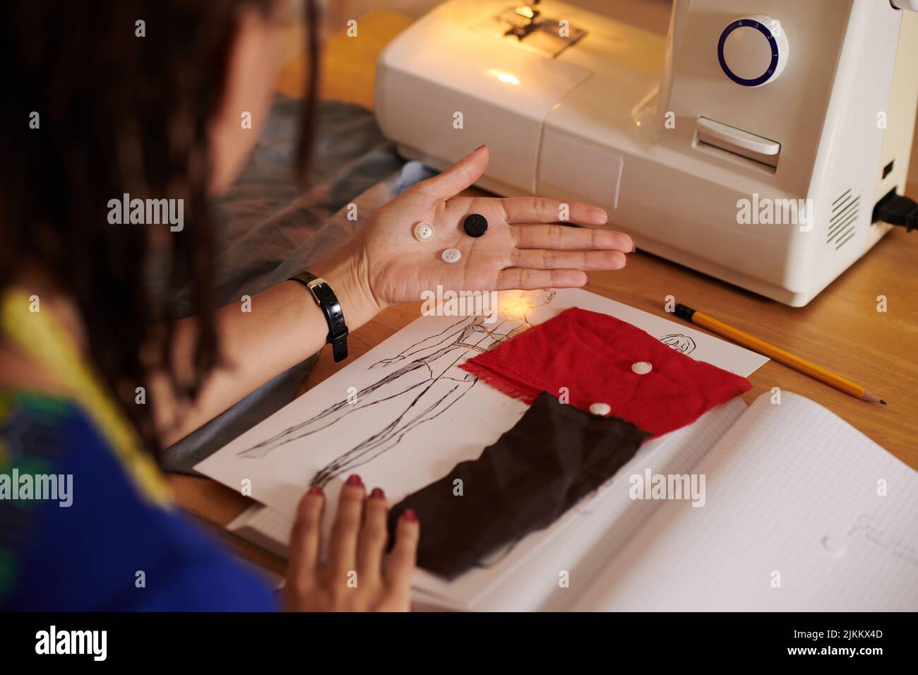 Closeup image of fashion designer choosing buttons for garment she is ...
