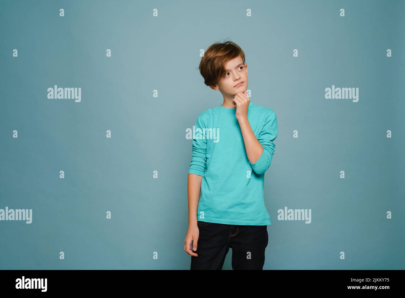 Ginger puzzled boy wearing long sleeve posing and looking aside ...