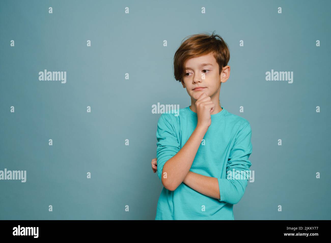 Ginger puzzled boy wearing long sleeve posing and looking aside ...
