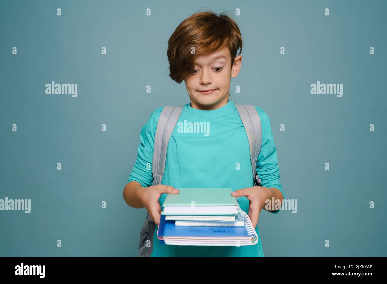 Ginger perplexed boy with backpack posing with exercise books isolated ...