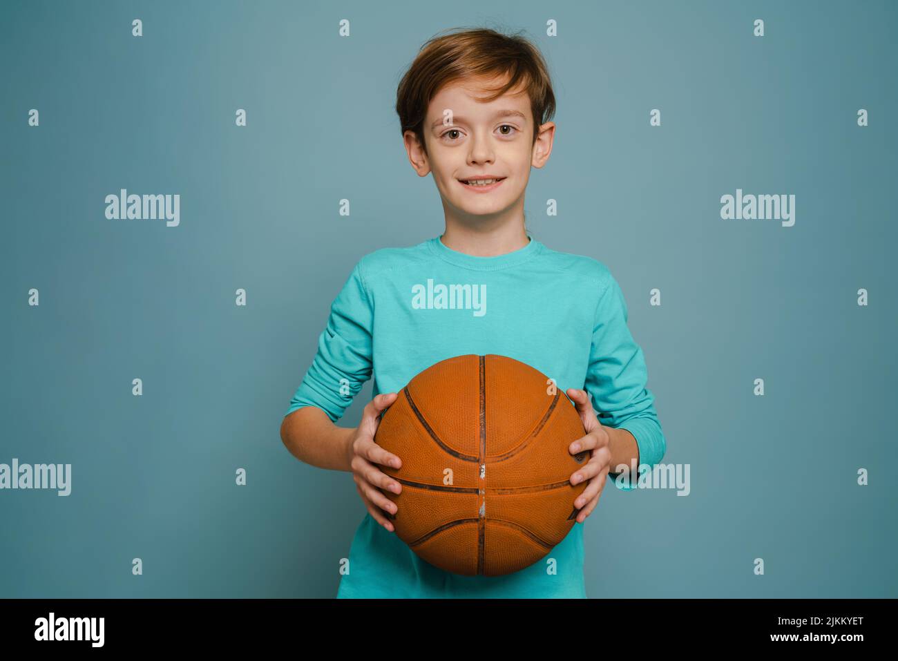 Ginger white boy smiling while posing with basketball isolated over ...