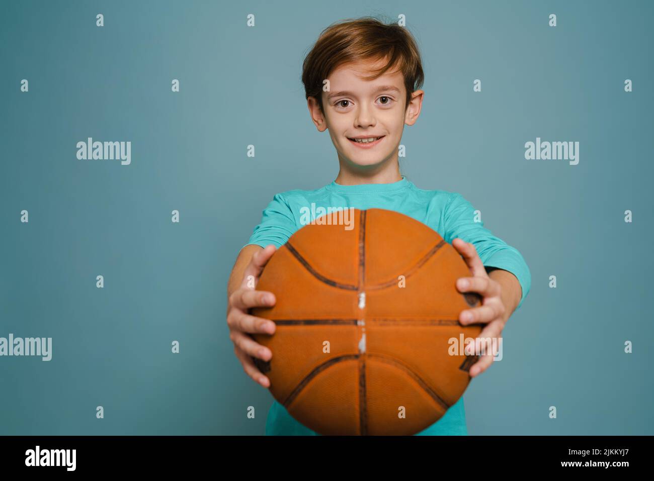 Ginger white boy smiling while posing with basketball isolated over ...