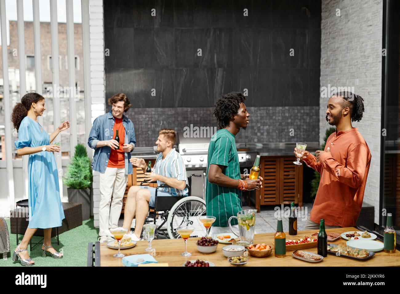 Diverse group of friends enjoying party at outdoor terrace and ...