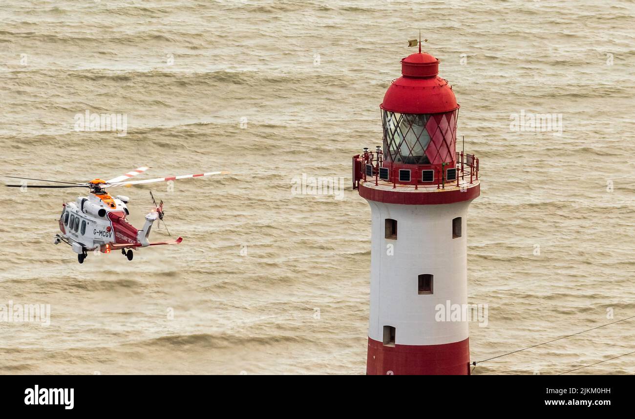 Coastguard helicopter hovering near lighthouse below the cliffs at ...
