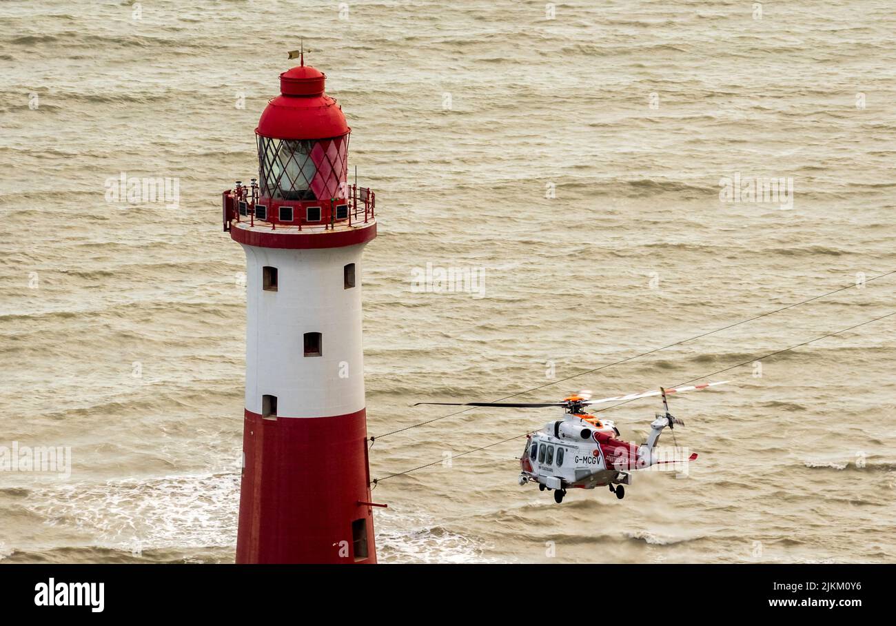 Coastguard helicopter hovering near lighthouse below the cliffs at ...
