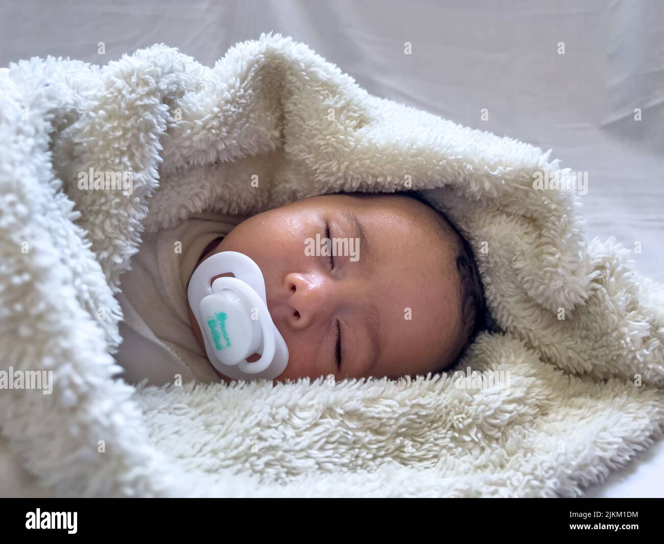Sweet peaceful baby lying on a white bedsheet enjoy daytime slumber ...