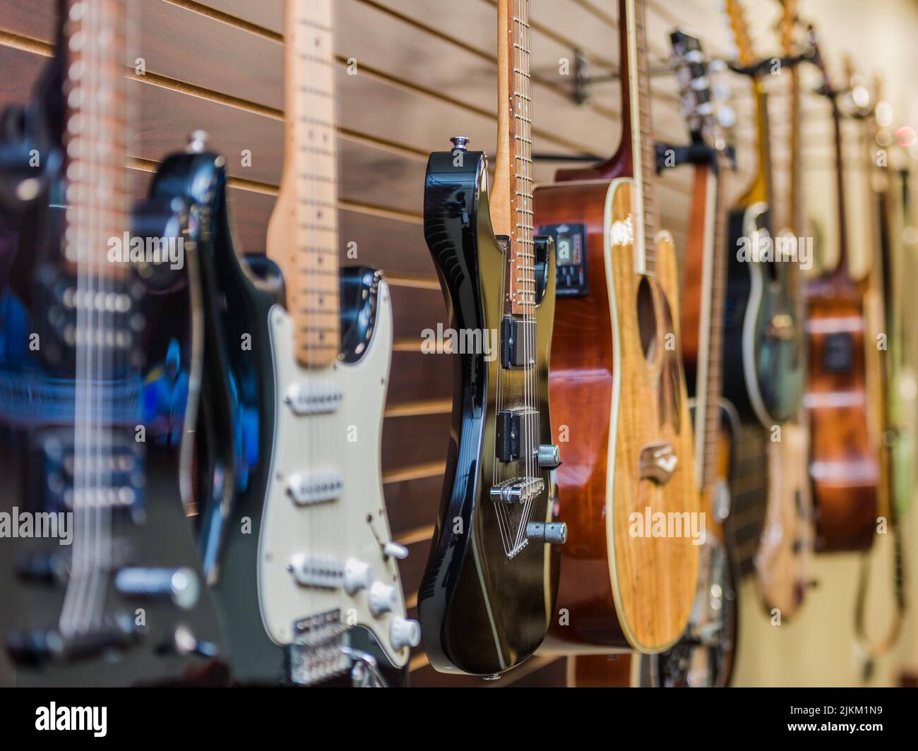 A closeup shot of the various types of guitars hanging on the wall in ...
