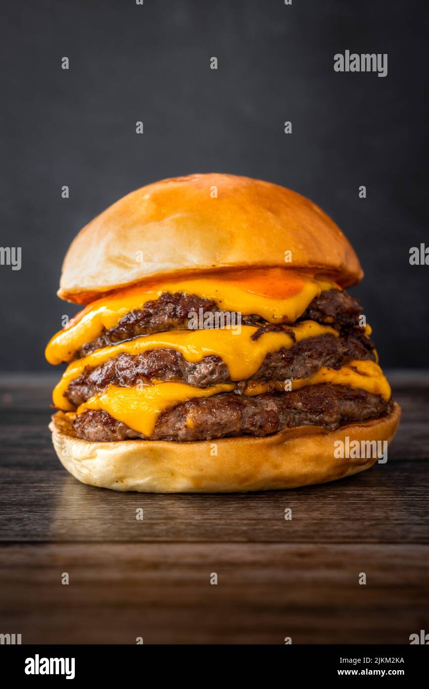 A vertical shot of a delicious juicy burger with triple patty on a ...