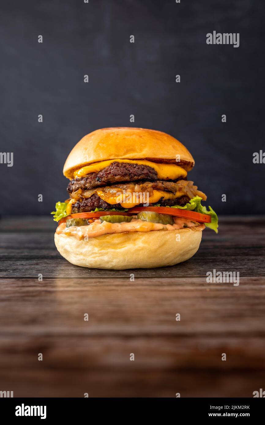 A vertical shot of a burger with bacon, fries, lettuce, melted cheese ...